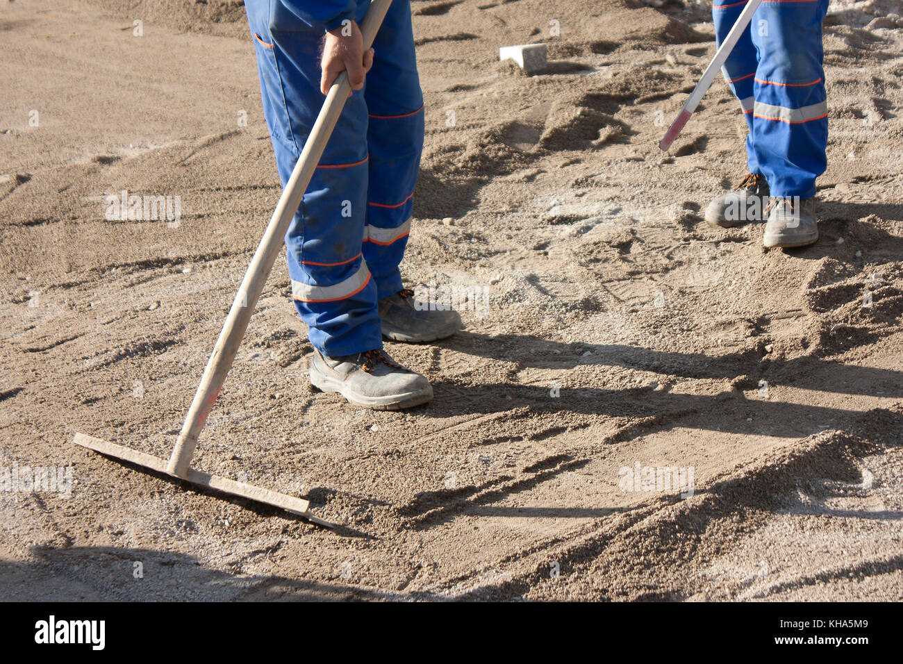 Construction site: Road paving preparation, two workers flattening the ...