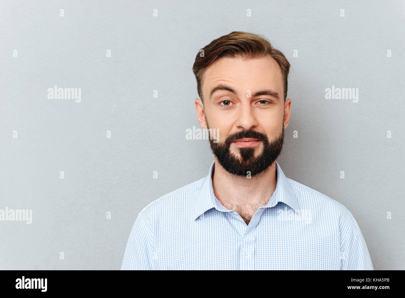 Quizzical bearded man in business clothes looking at the camera over ...