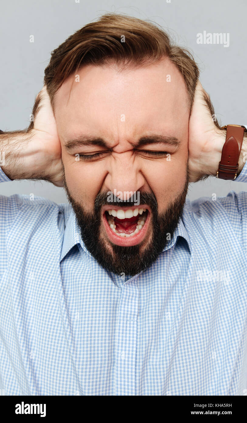 Vertical image of screaming bearded man in business clothes covering ...