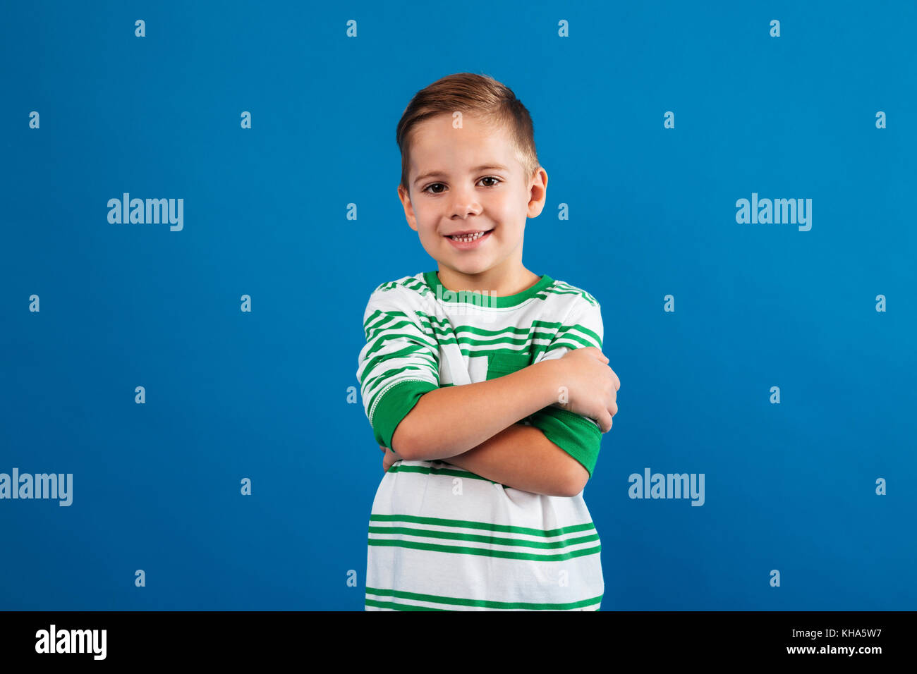 Portrait of a smiling young kid standing with arms folded isolated over ...