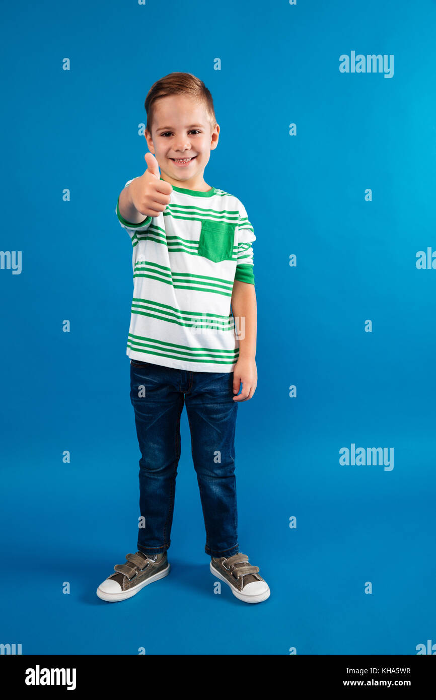 Full length portrait of a funny young kid standing and showing thumbs ...