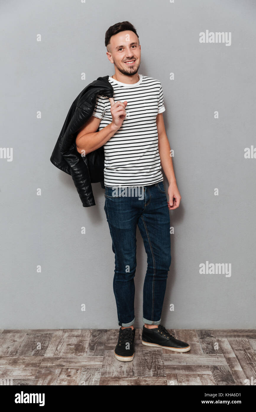 Full length image of smiling man holding his jacket on shoulder and ...