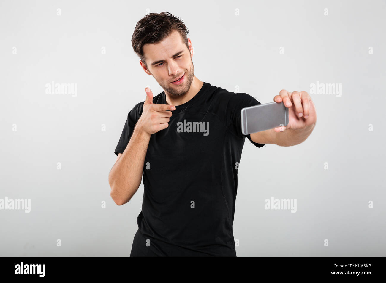 Portrait of a young confident man pointing finger while making a selfie ...