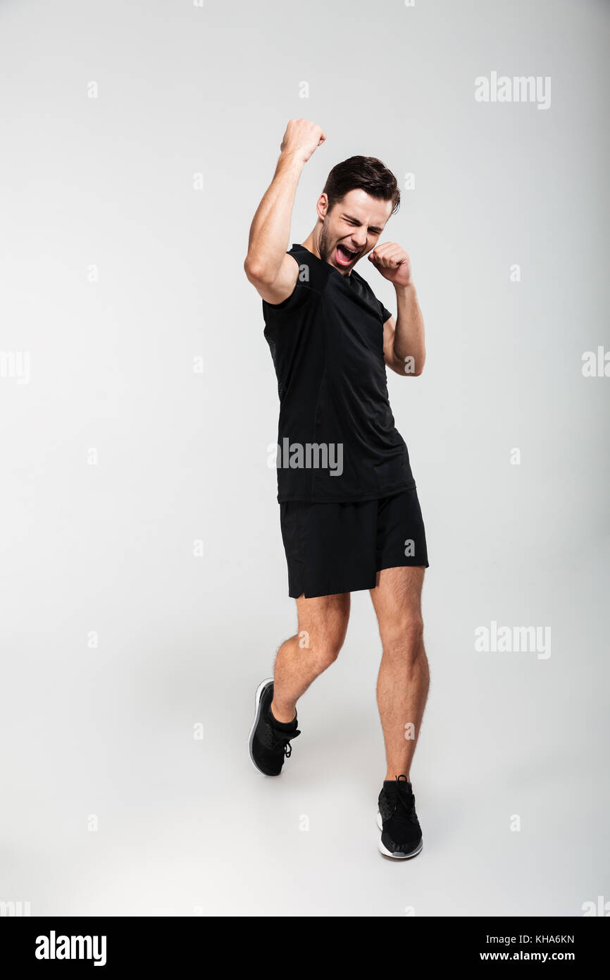 Full length portrait of a pleased happy sportsman celebrating success ...