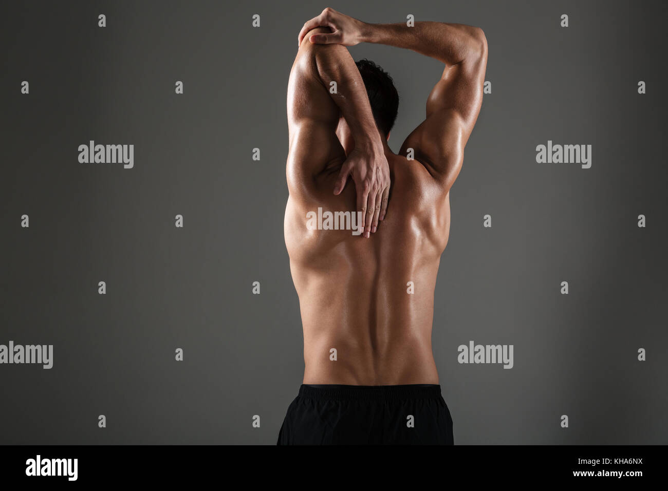 Back view image of young sports man posing isolated over grey wall ...