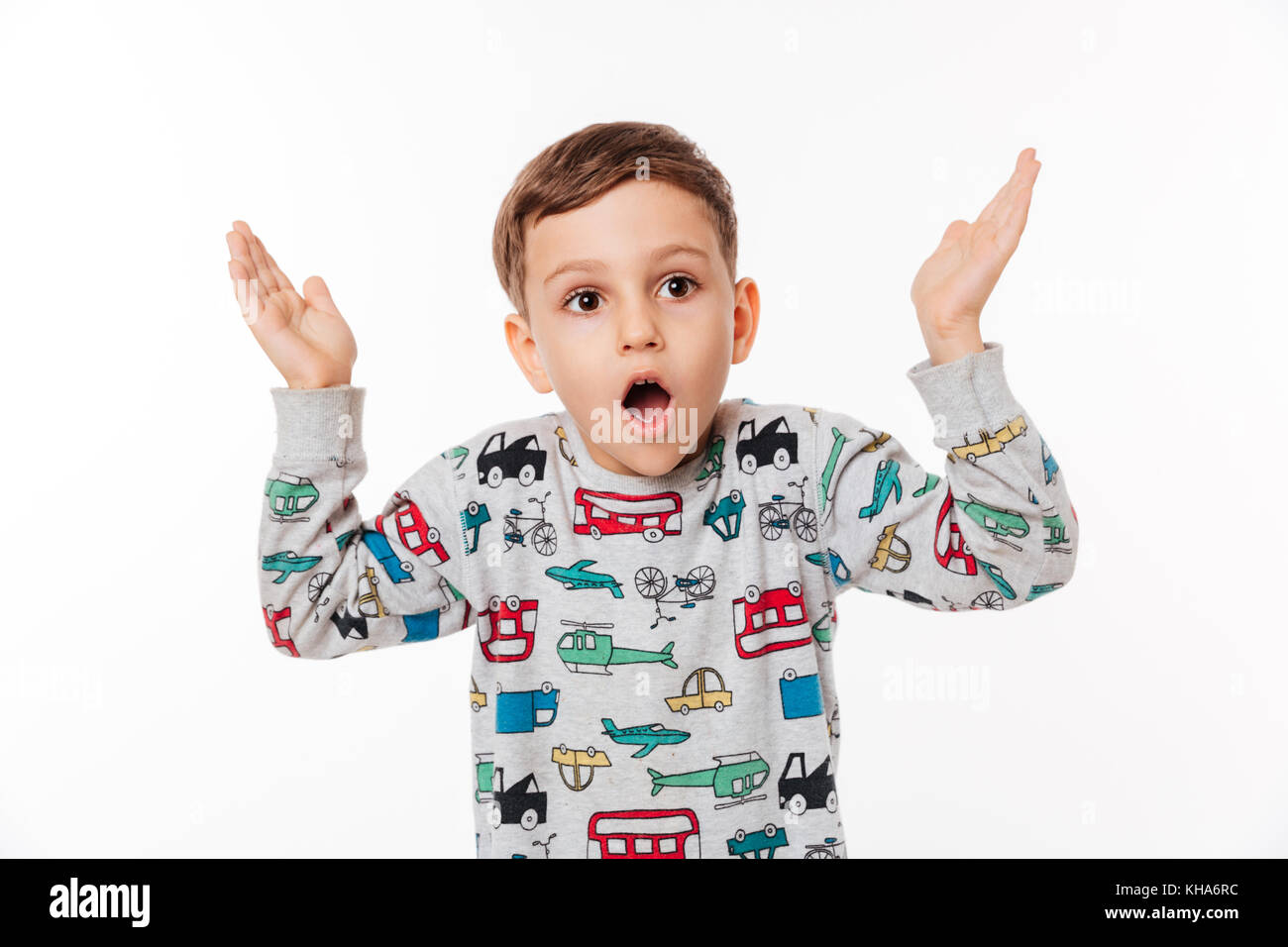 Portrait of a shocked little kid standing and shrugging shoulders ...