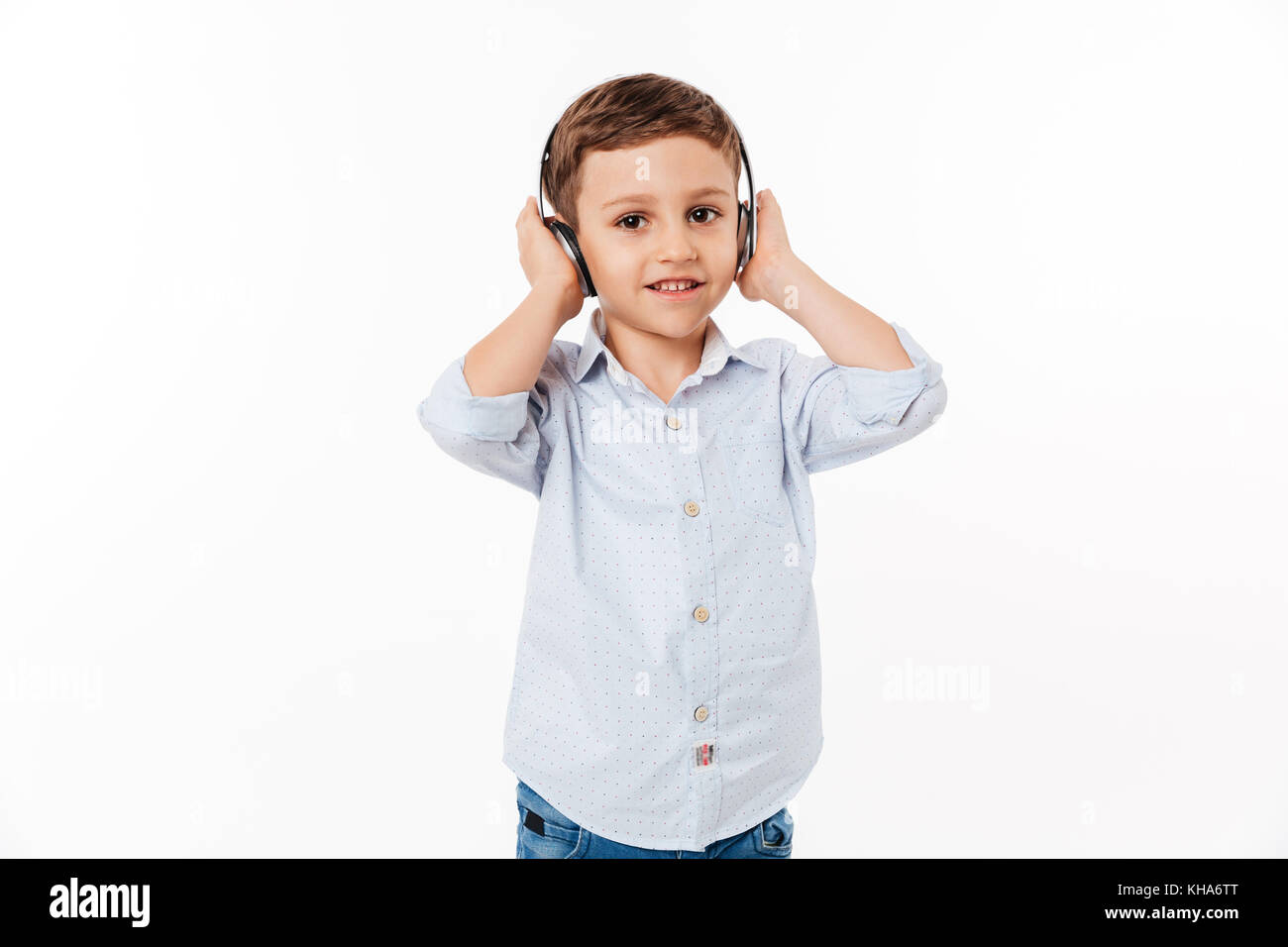 Portrait of a cute little kid in headphones listening to music and ...