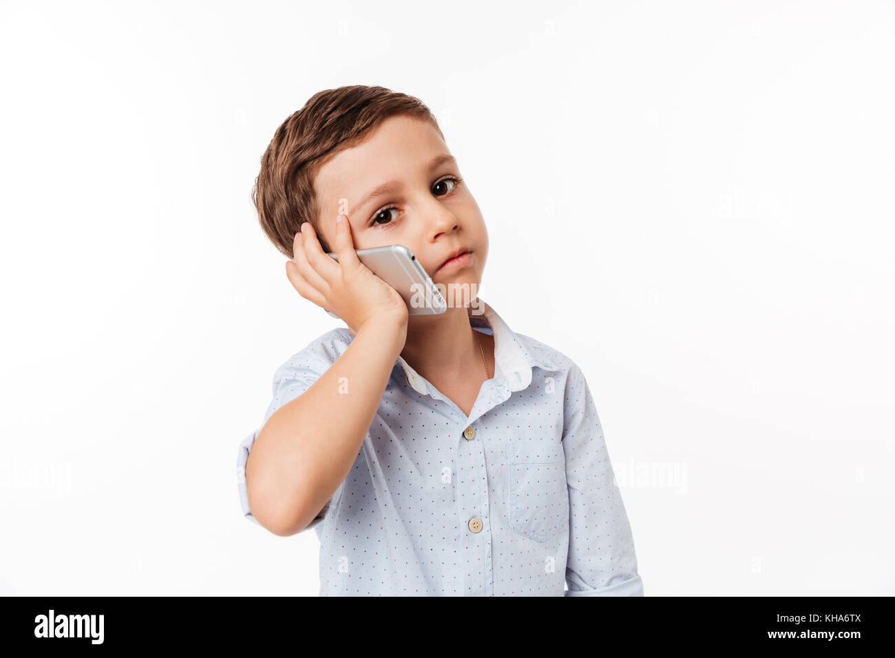 Portrait of a cute little kid talking on mobile phone and looking at ...