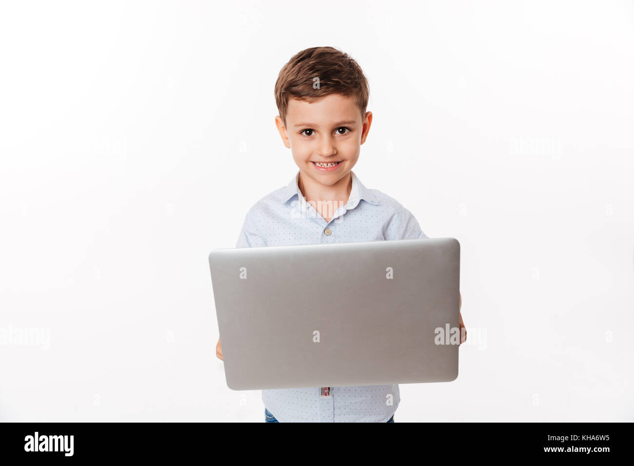 Portrait of a happy cute little kid holding laptop computer while ...