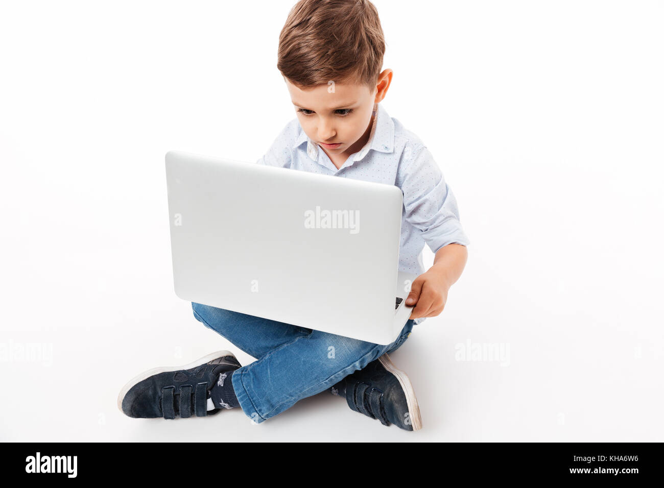 Portrait of a cute little kid using laptop computer while sitting on a ...