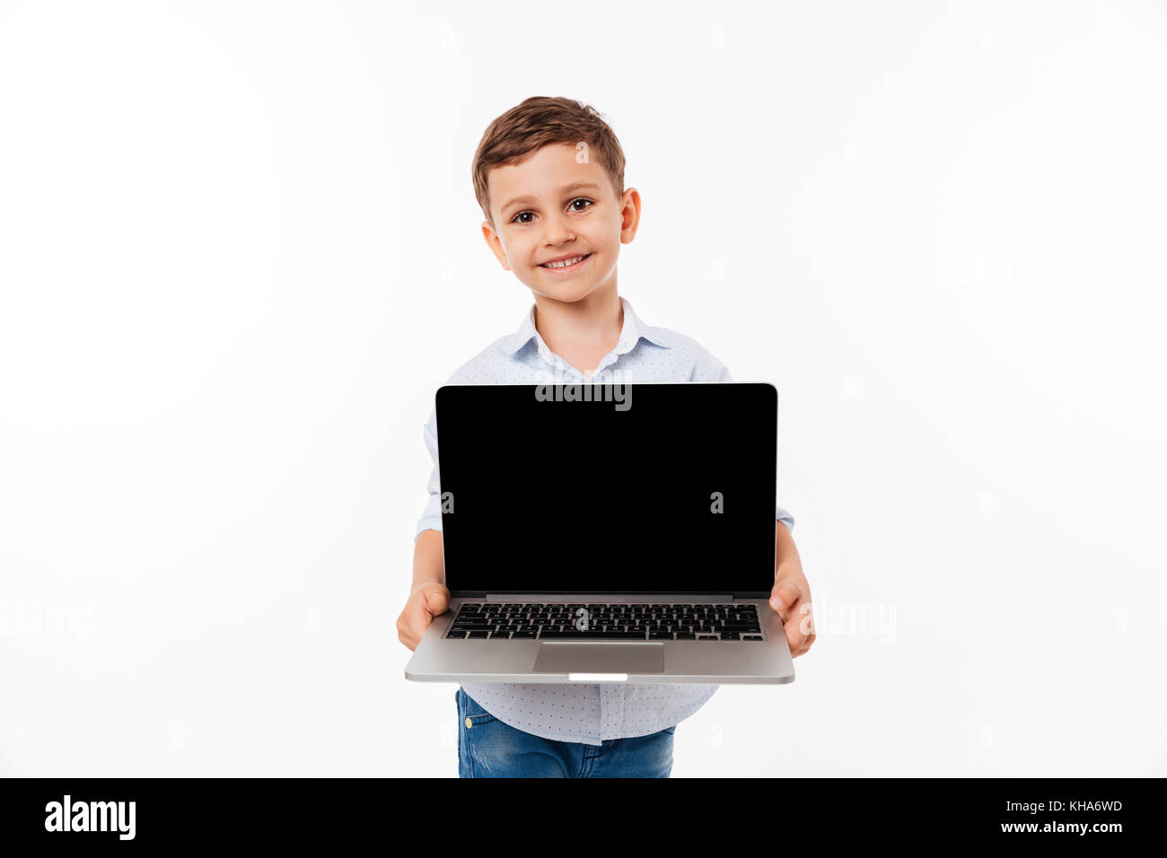 Portrait of a cheerful cute little kid showing blank screen laptop ...