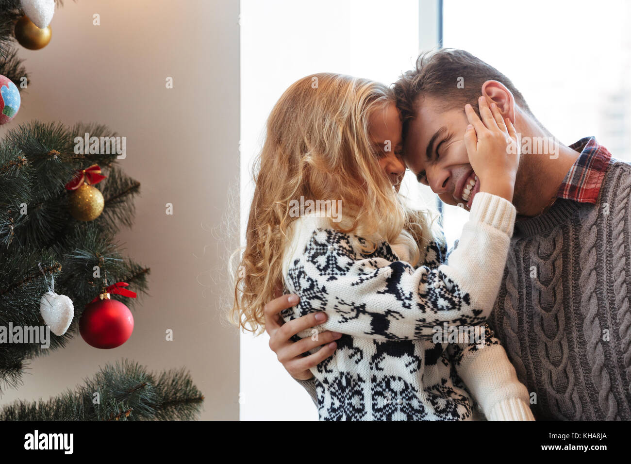 Cute blonde girl touching fathers face with closed eyes near Christmas ...