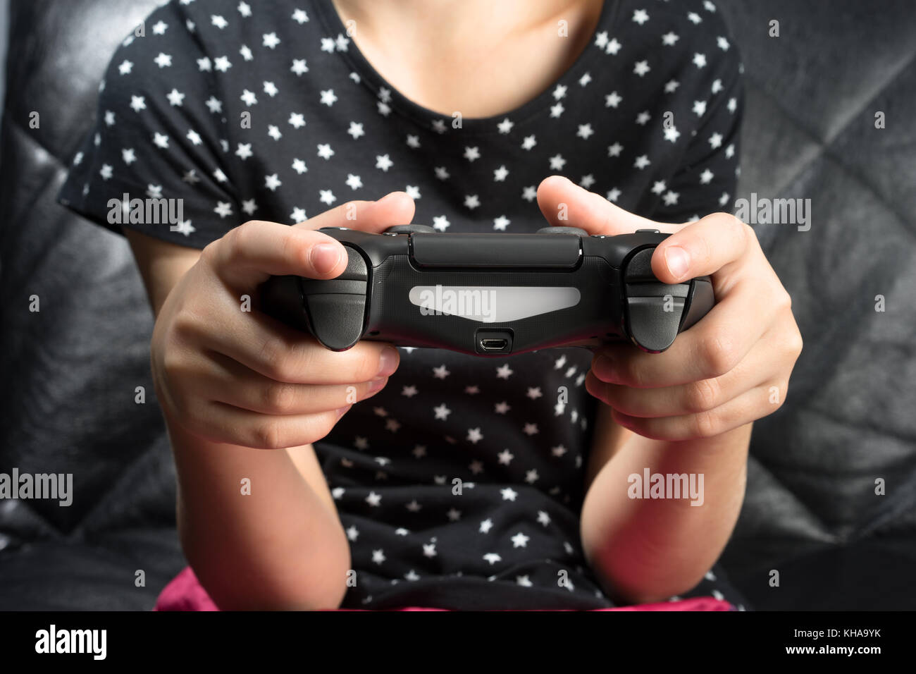 Child girl is playing video games and holds joystick or controller ...