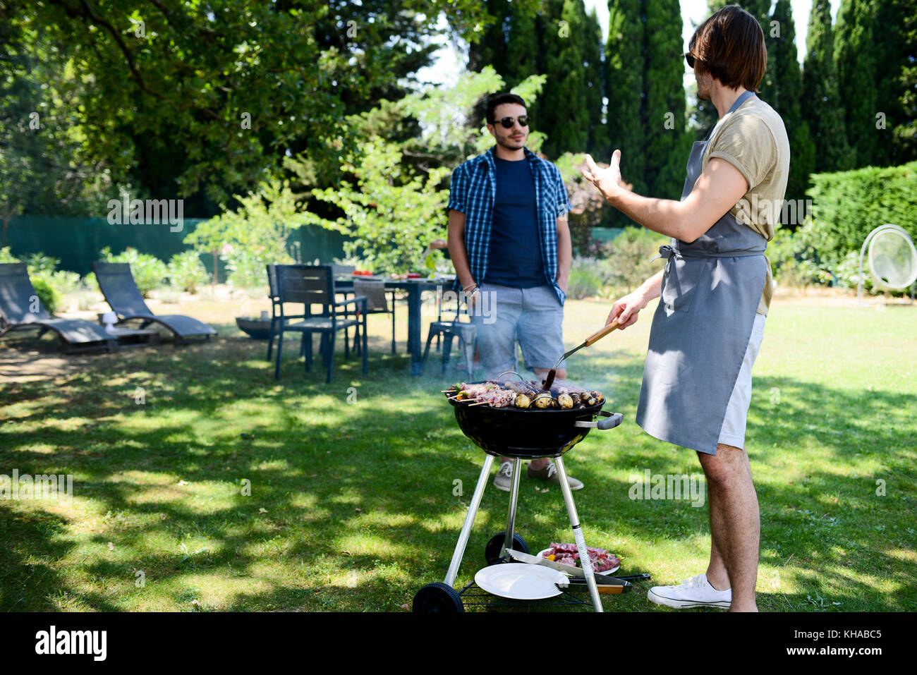 Handsome young man cooking meat in a barbecue party outdoor in the ...