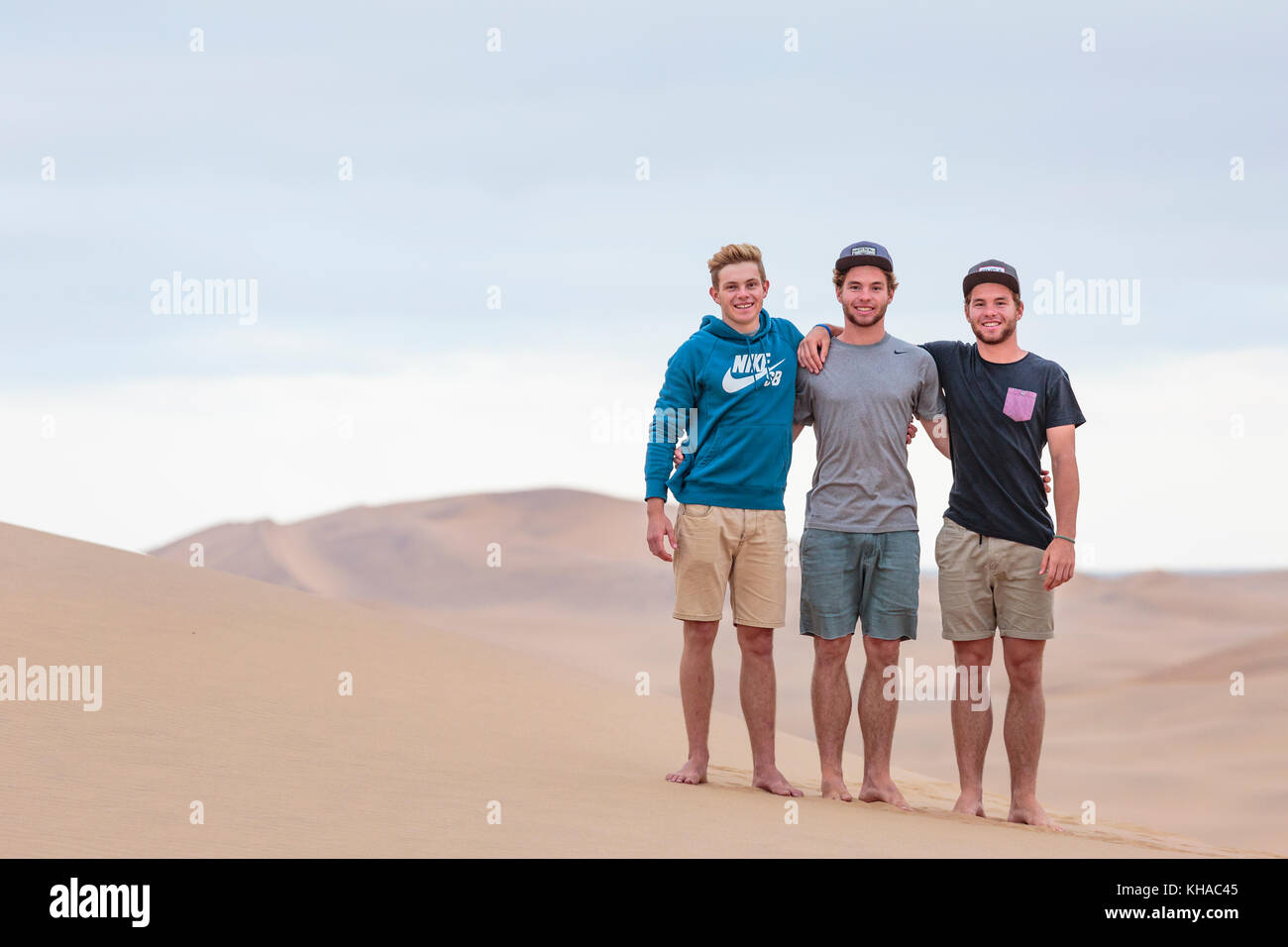 Three young men on sand dune, Namib Desert, Namibia Stock Photo - Alamy