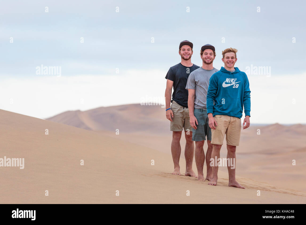 Three young men on sand dune, Namib Desert, Namibia Stock Photo - Alamy
