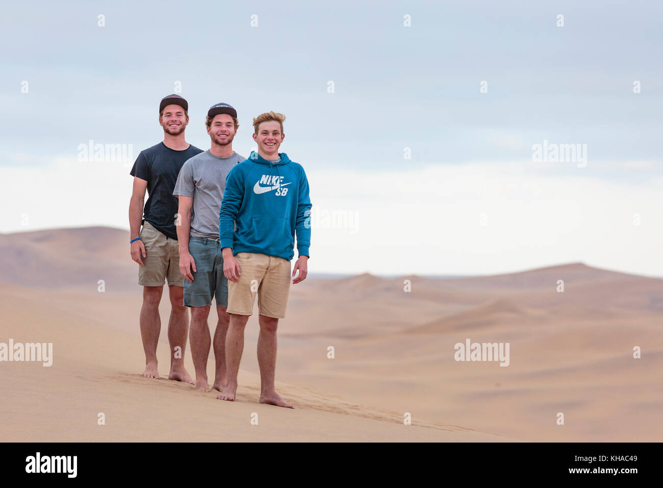 Three young men on sand dune, Namib Desert, Namibia Stock Photo - Alamy