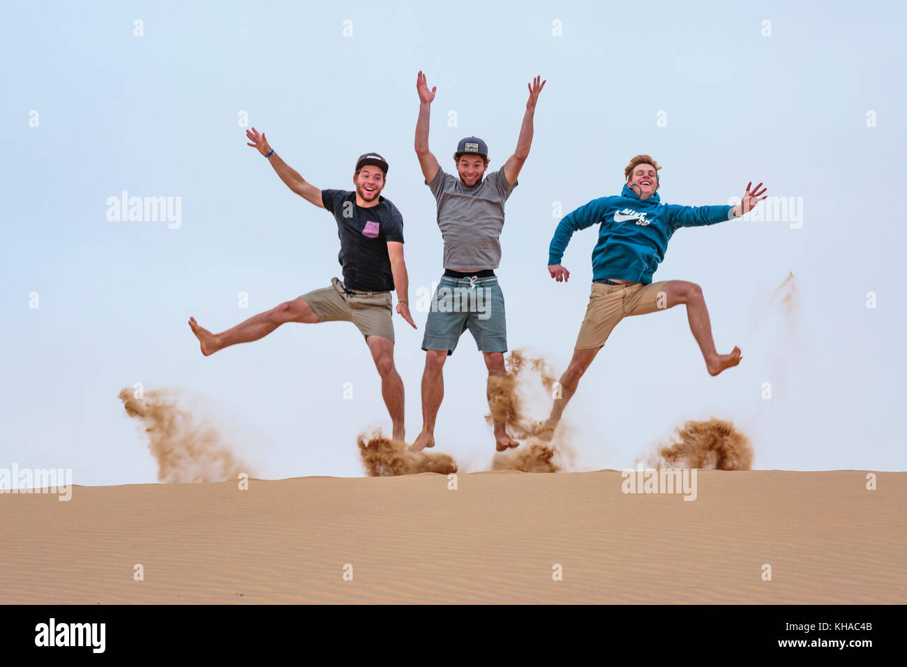 Three young men jumping in the sand, Namib Desert, Namibia Stock Photo ...