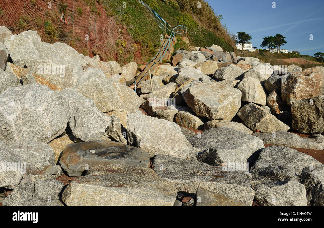 Rock armour - large boulders piled against red sandstone cliffs to ...