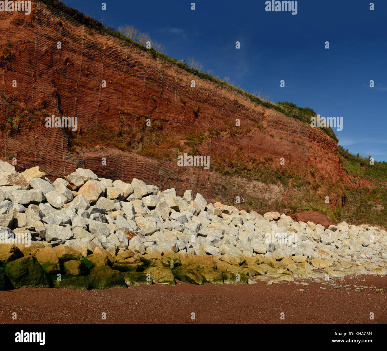 Rock armour - large boulders piled against red sandstone cliffs to ...