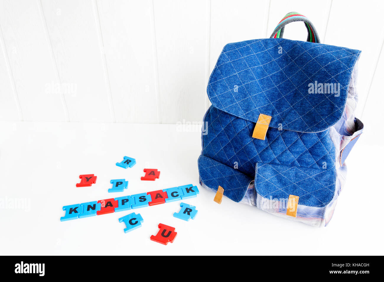 Blue bag with puzzle letters on white table. Hand made backpack Stock ...