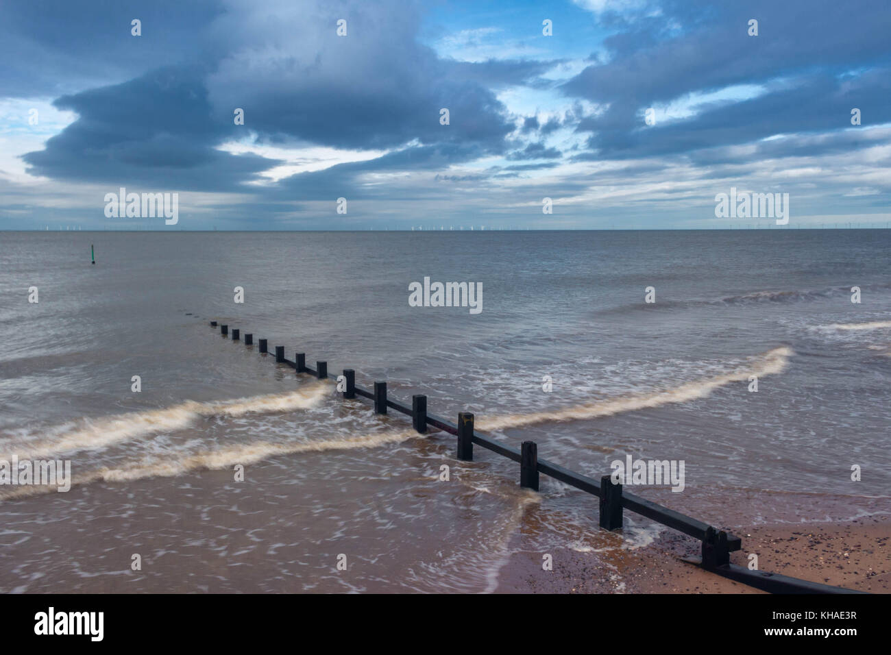 a wooden structure sea defence going from the beach into the rough sea ...