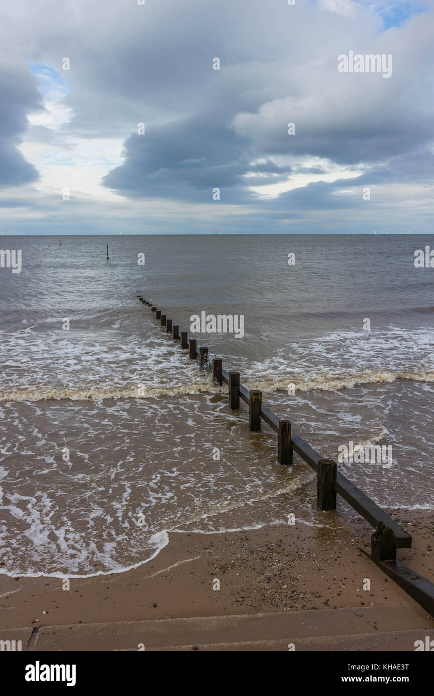 a wooden structure sea defence going from the beach into the rough sea ...