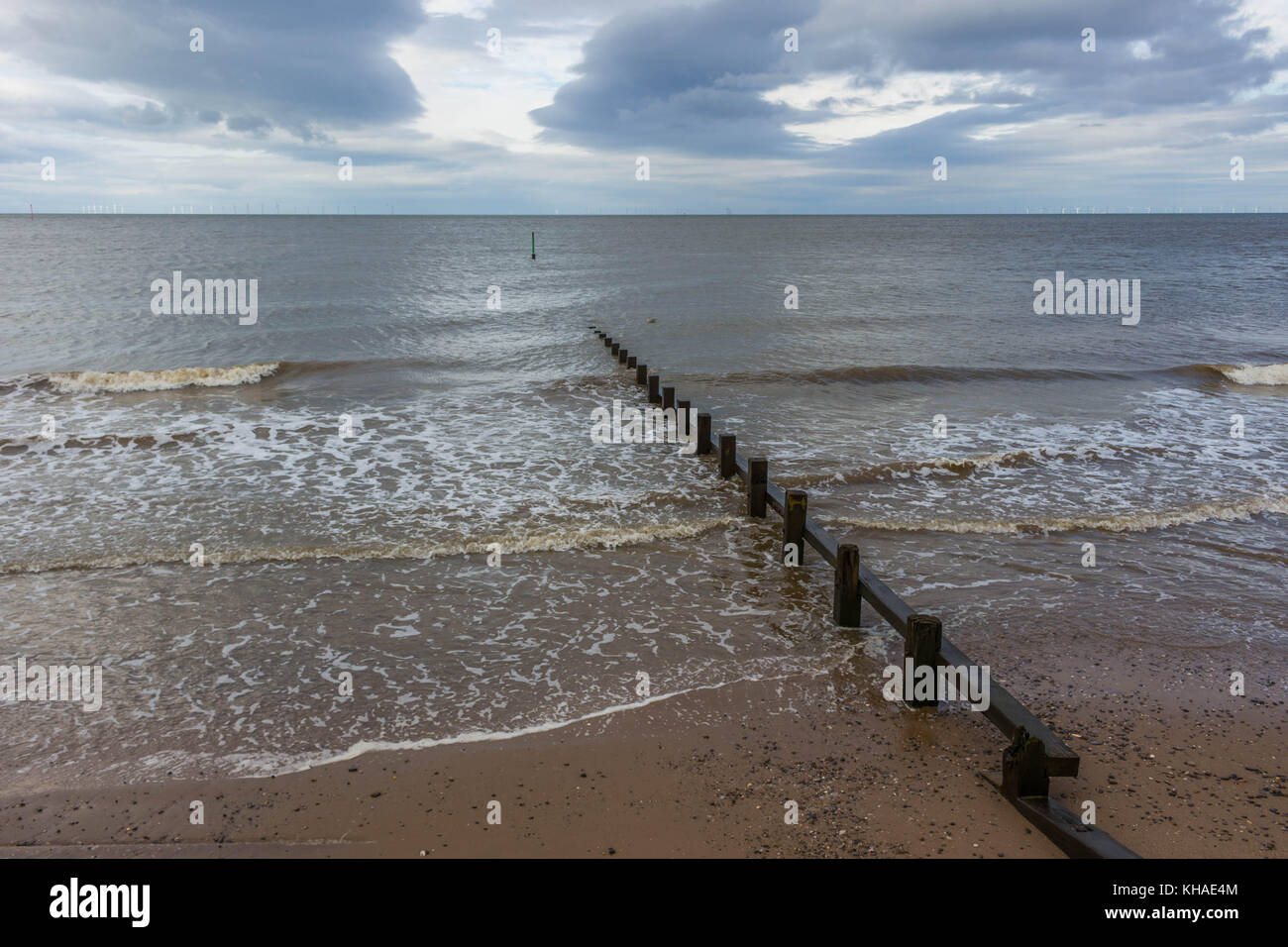 a wooden structure sea defence going from the beach into the rough sea ...