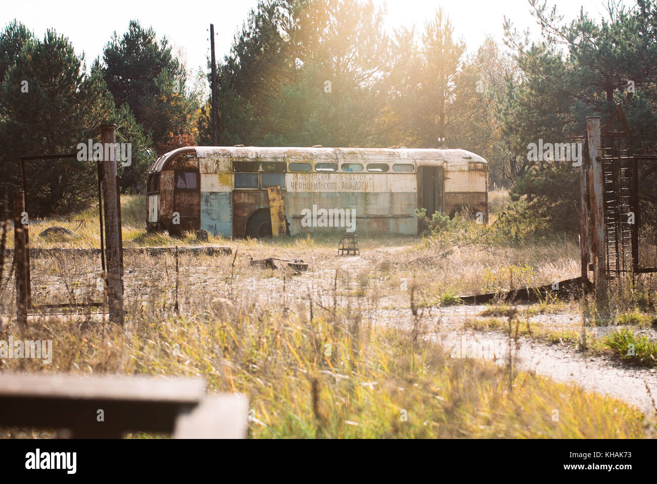 An abandoned, run down bus lies in an empty field of long grass in the ...