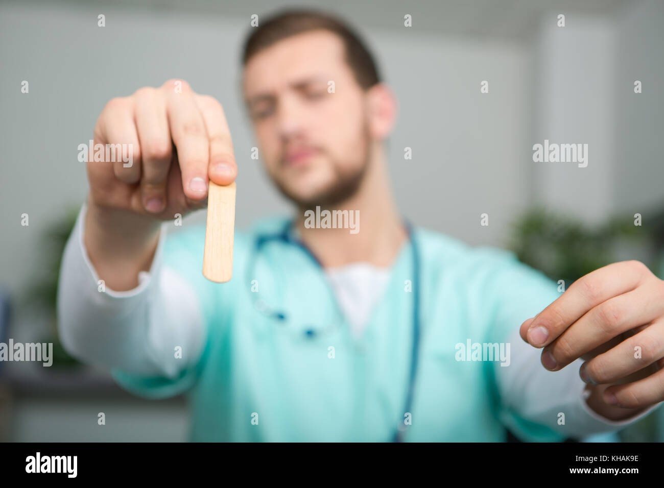 male doctor holding stick to look in patients throat Stock Photo - Alamy