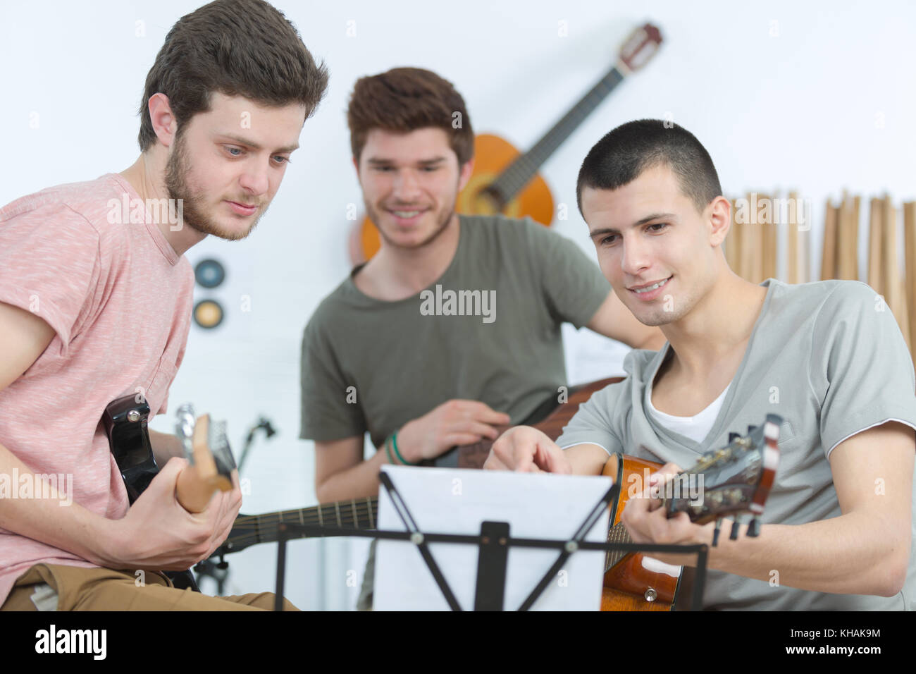 Three young male musicians looking at sheet music Stock Photo - Alamy