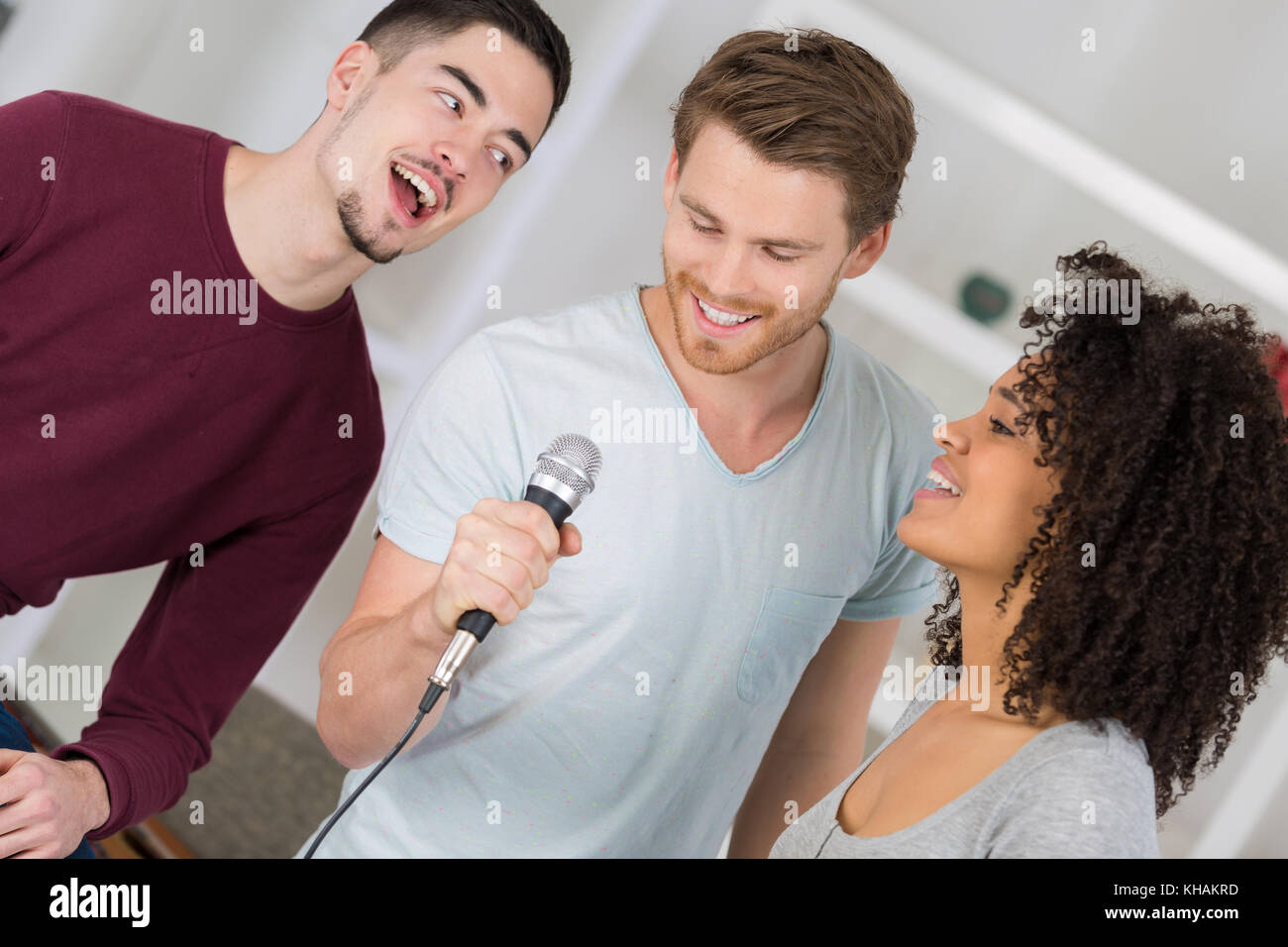 three young people singing into microphone Stock Photo - Alamy