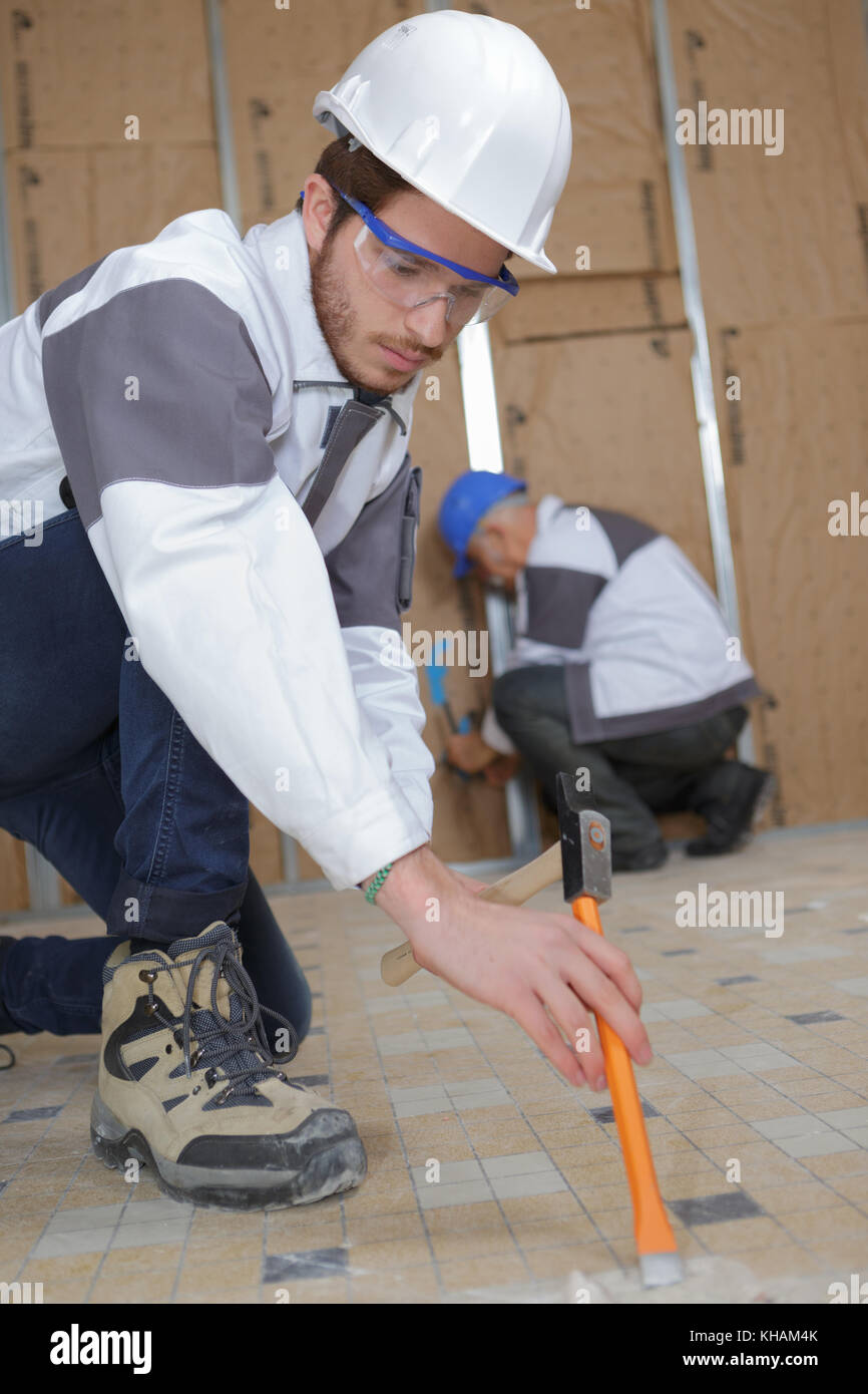 flooring tile setter removing the old tiles Stock Photo - Alamy