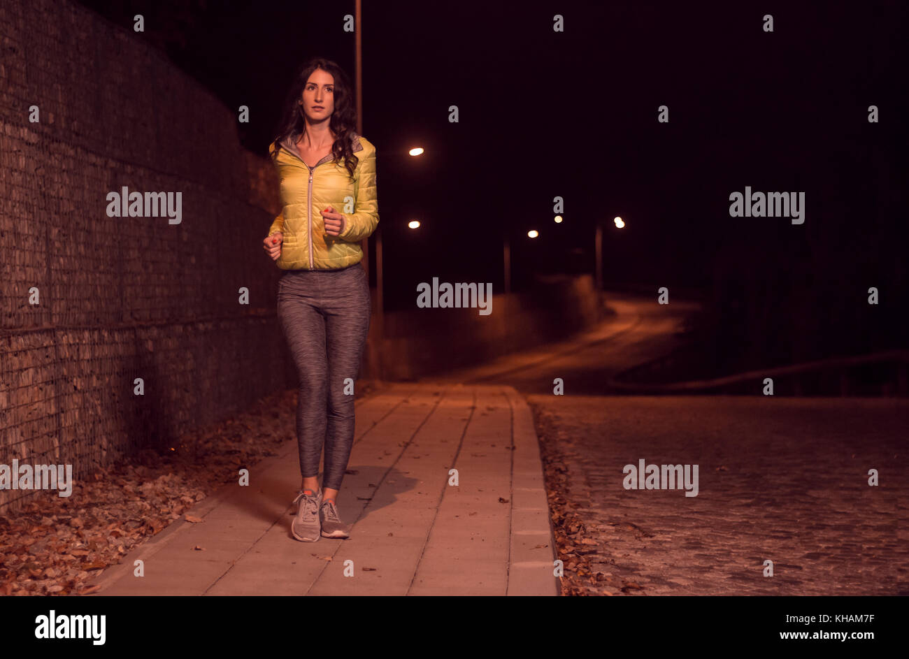 one young woman, alone one person, jogging sidewalk, outdoors night ...