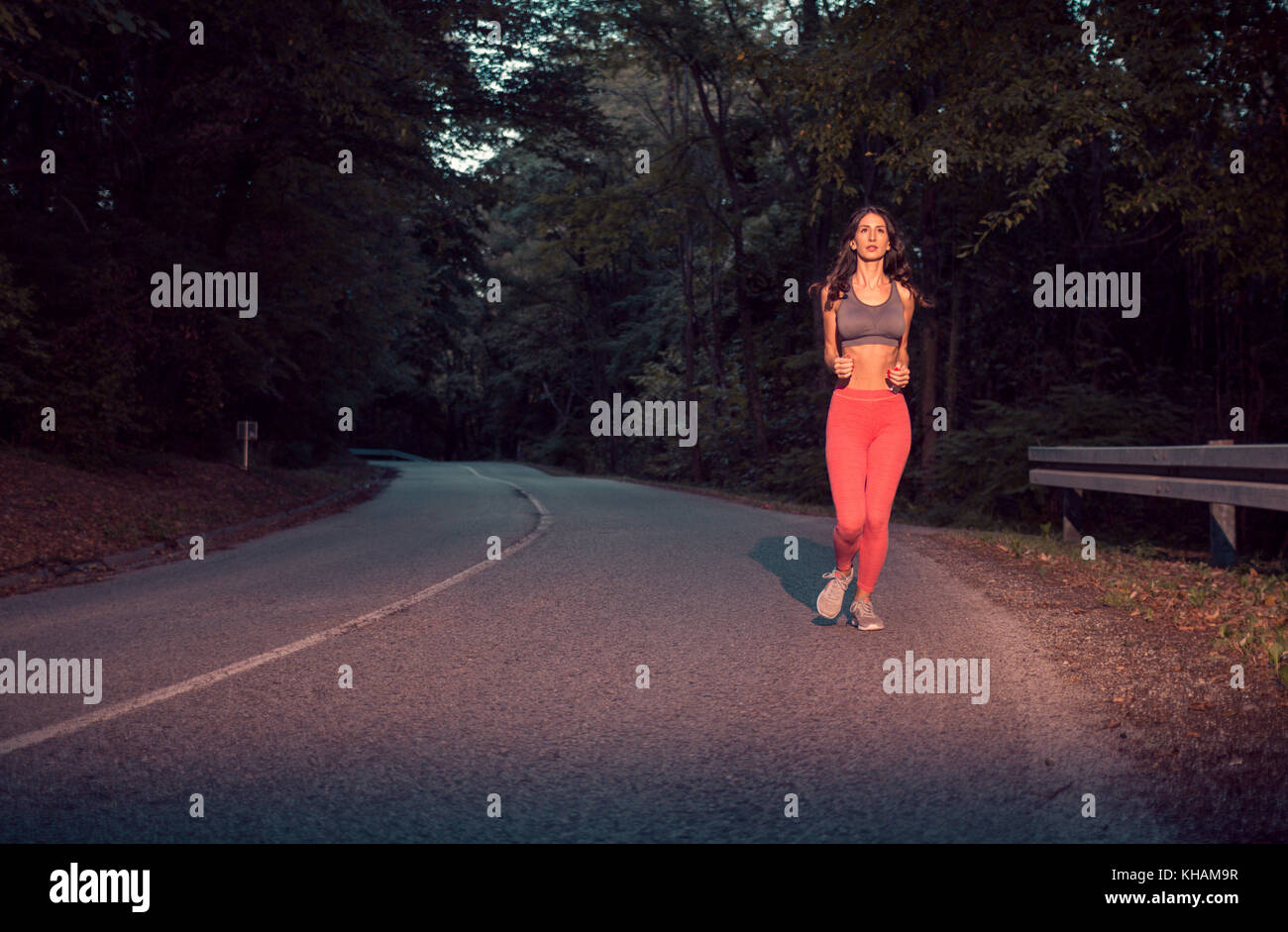 one young adult woman, jogging running on asphalt road, outdoors night ...