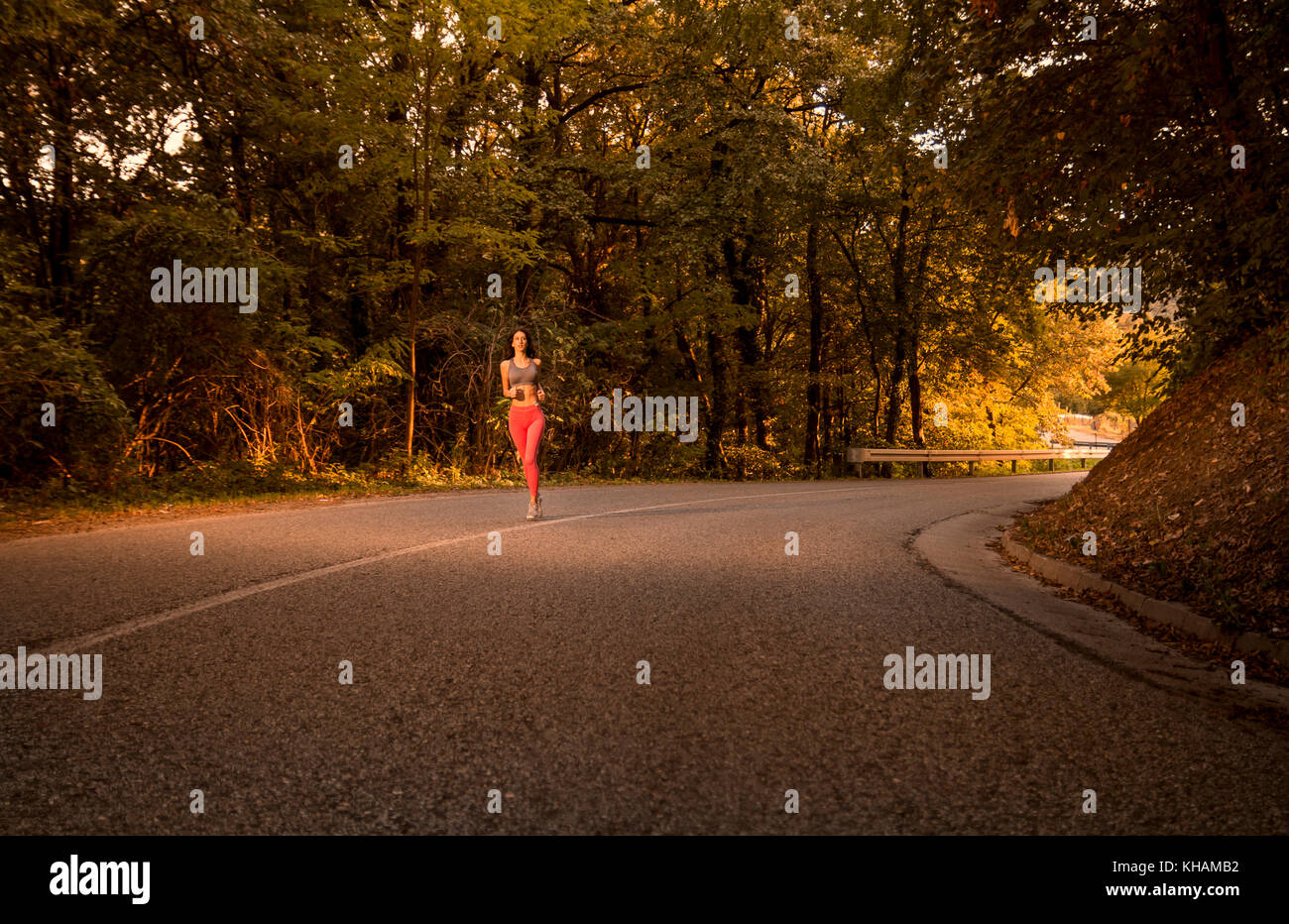 one young woman, outdoors jogging running on asphalt road, forest woods ...