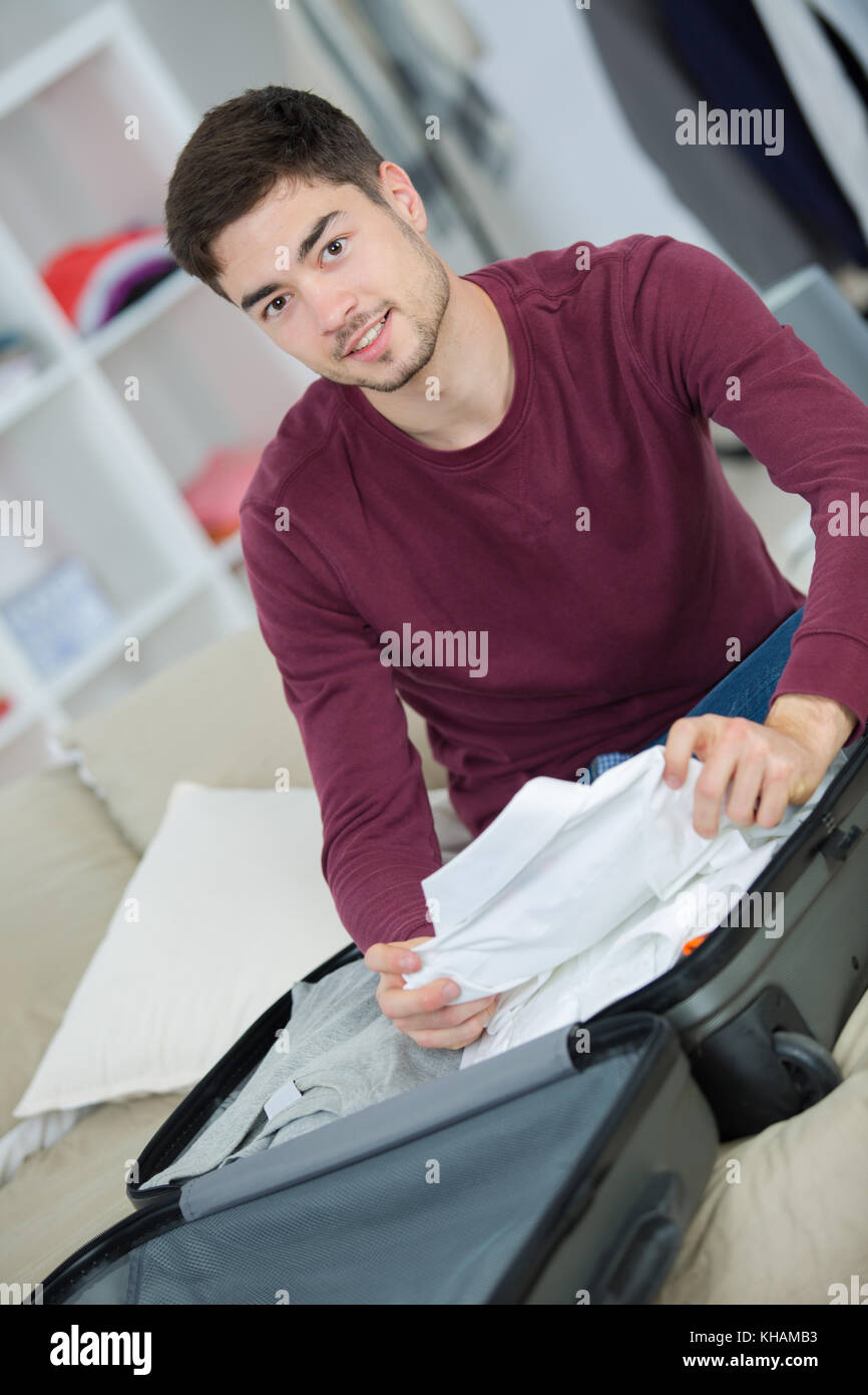 man packing his grey suitcase in living room Stock Photo - Alamy