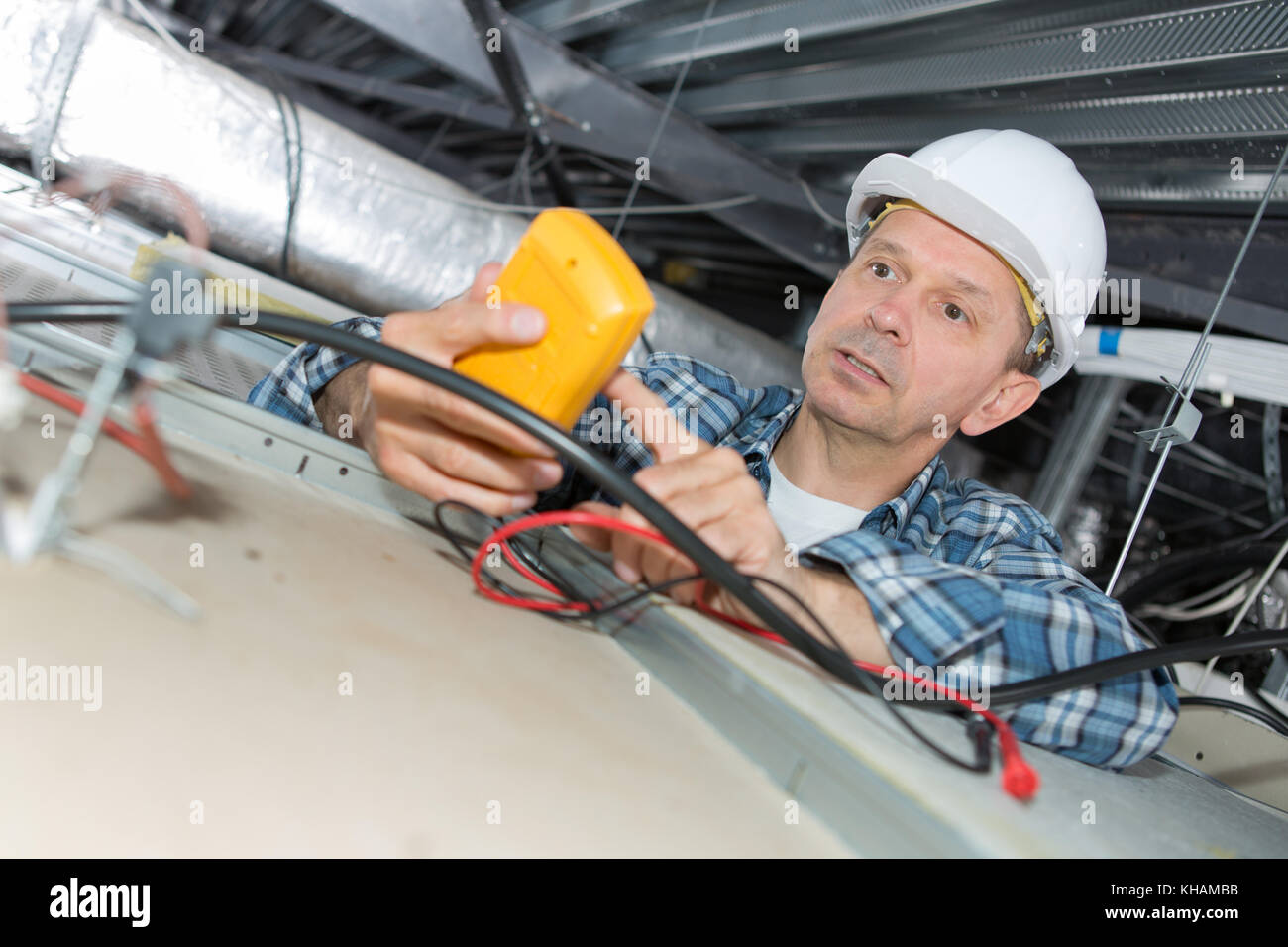 electrician inspecting the dead wires on the ceiling top Stock Photo ...