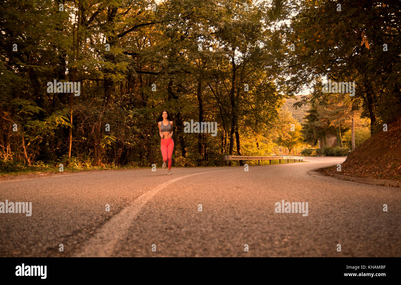 one young woman, outdoors jogging running on asphalt road, forest woods ...
