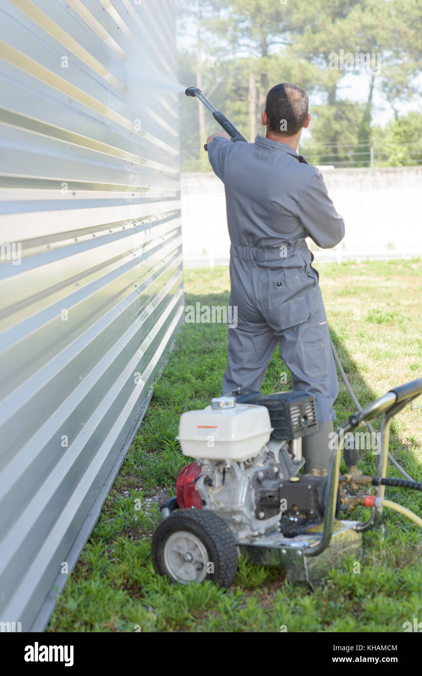 Man power washing side of building Stock Photo - Alamy