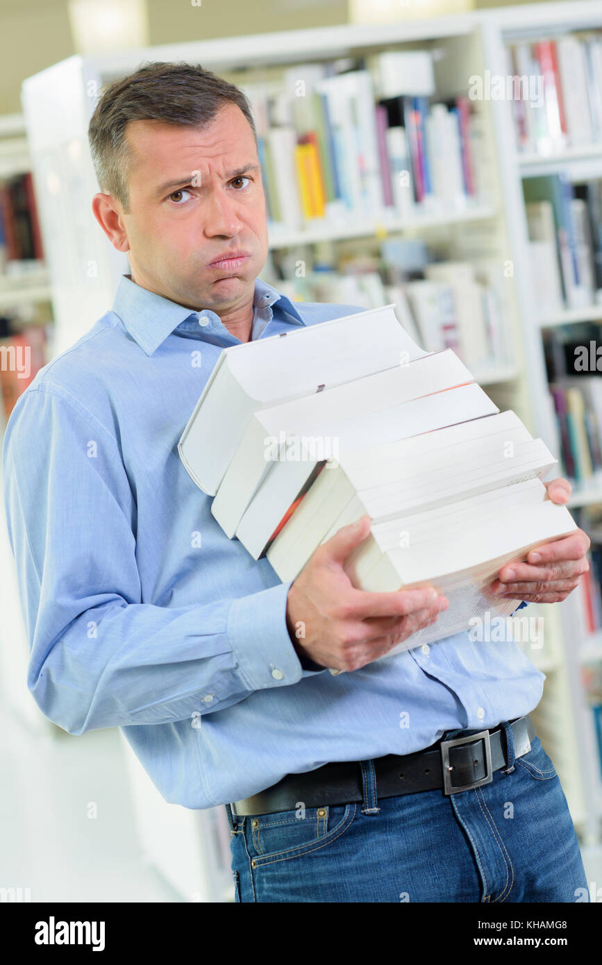 having difficulty carrying the books Stock Photo - Alamy