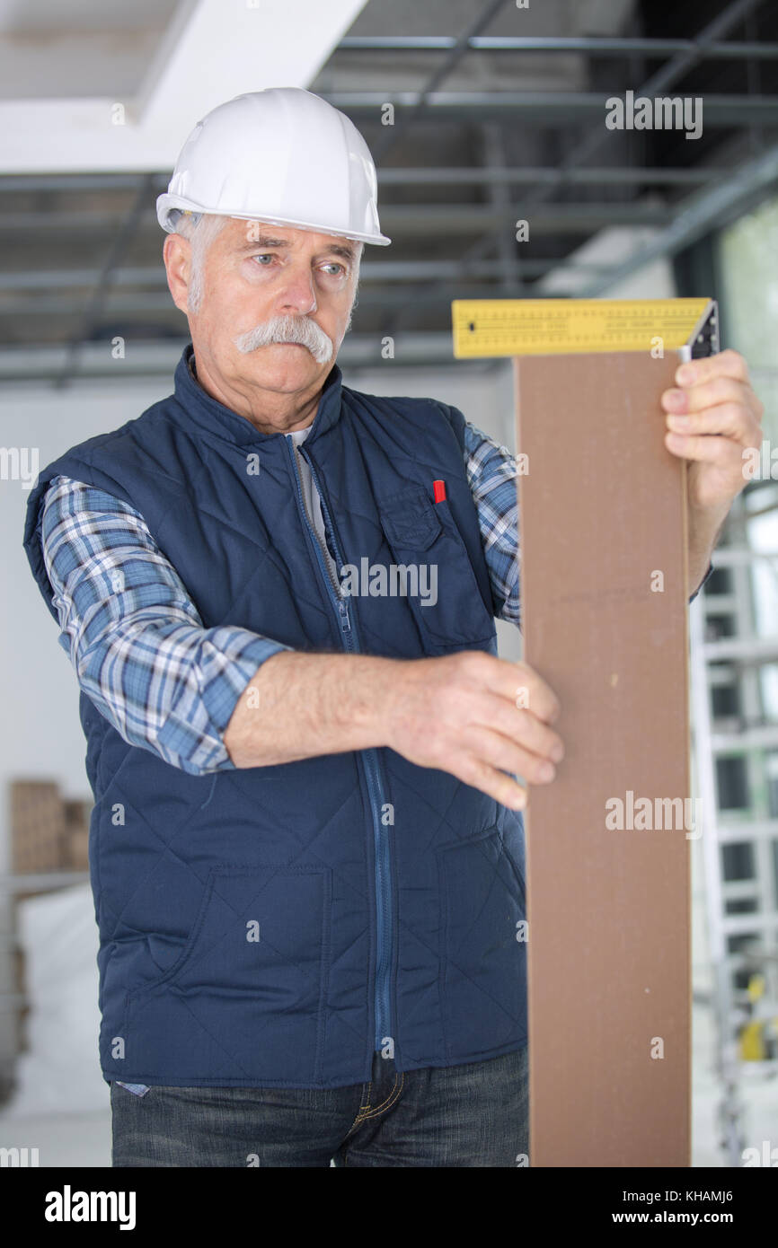 Senior worker measuring wood Stock Photo - Alamy