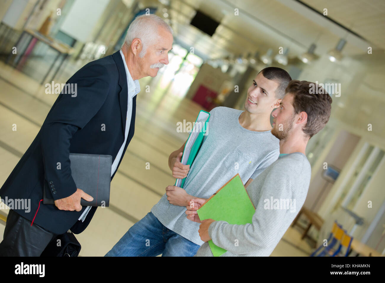 professor with notebook talking to a student in corridor Stock Photo ...