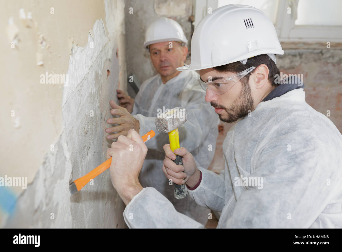 builder using hammer to remove plaster from a wall Stock Photo - Alamy