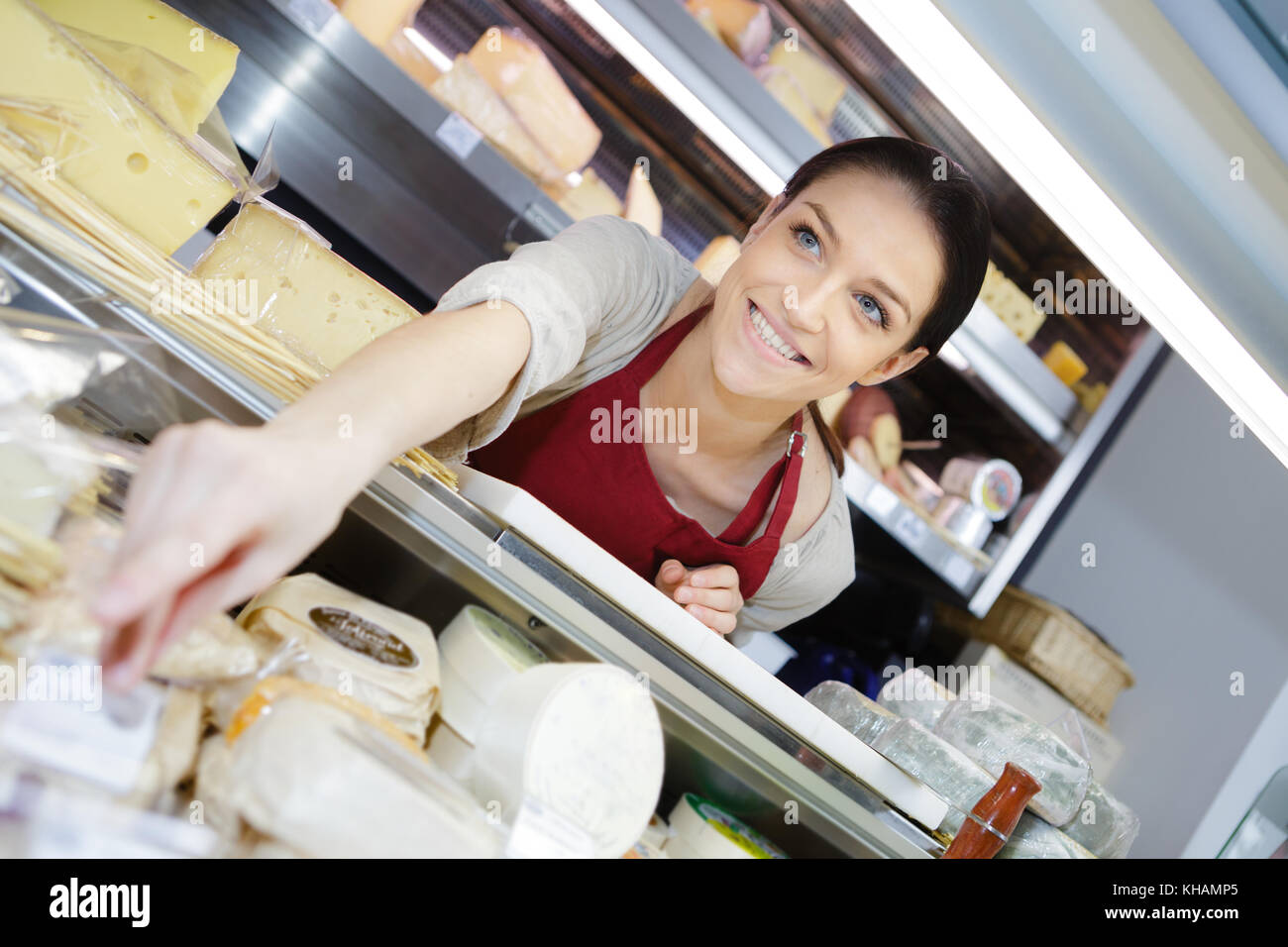 Sales assistant reaching into cheese counter Stock Photo - Alamy