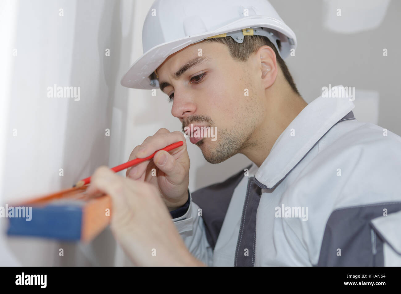 male construction worker marking on wooden plank at home Stock Photo ...