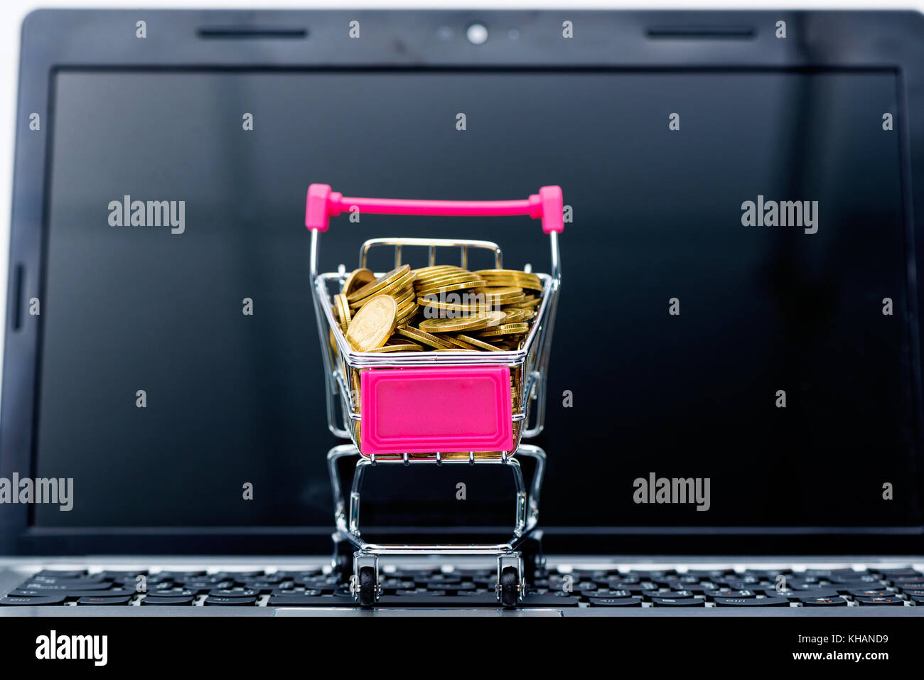 Stack of coins in shopping cart or supermarket trolley with laptop ...