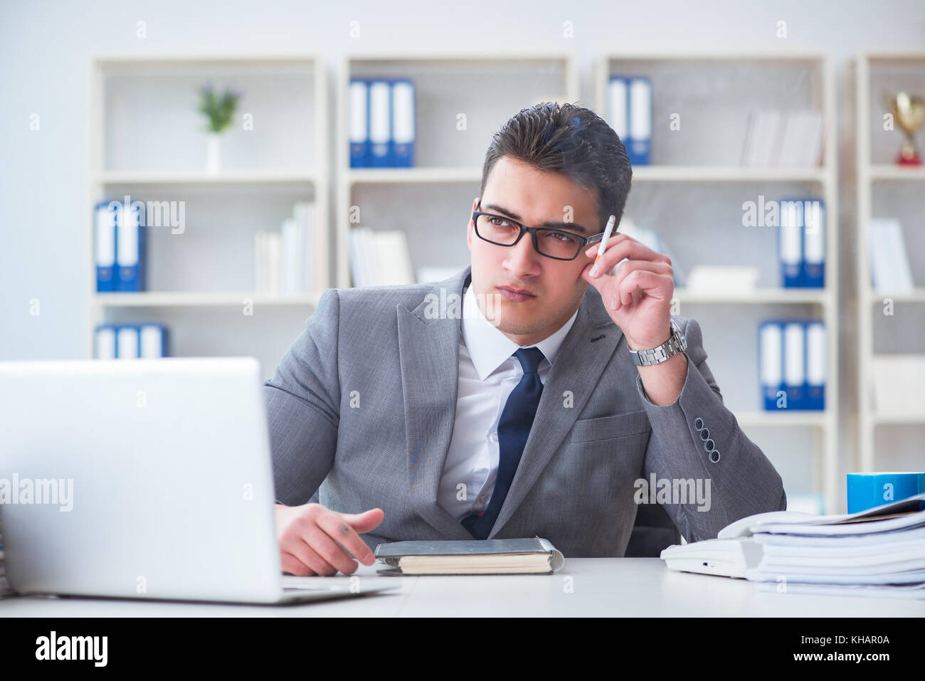 Businessman smoking in office at work Stock Photo - Alamy
