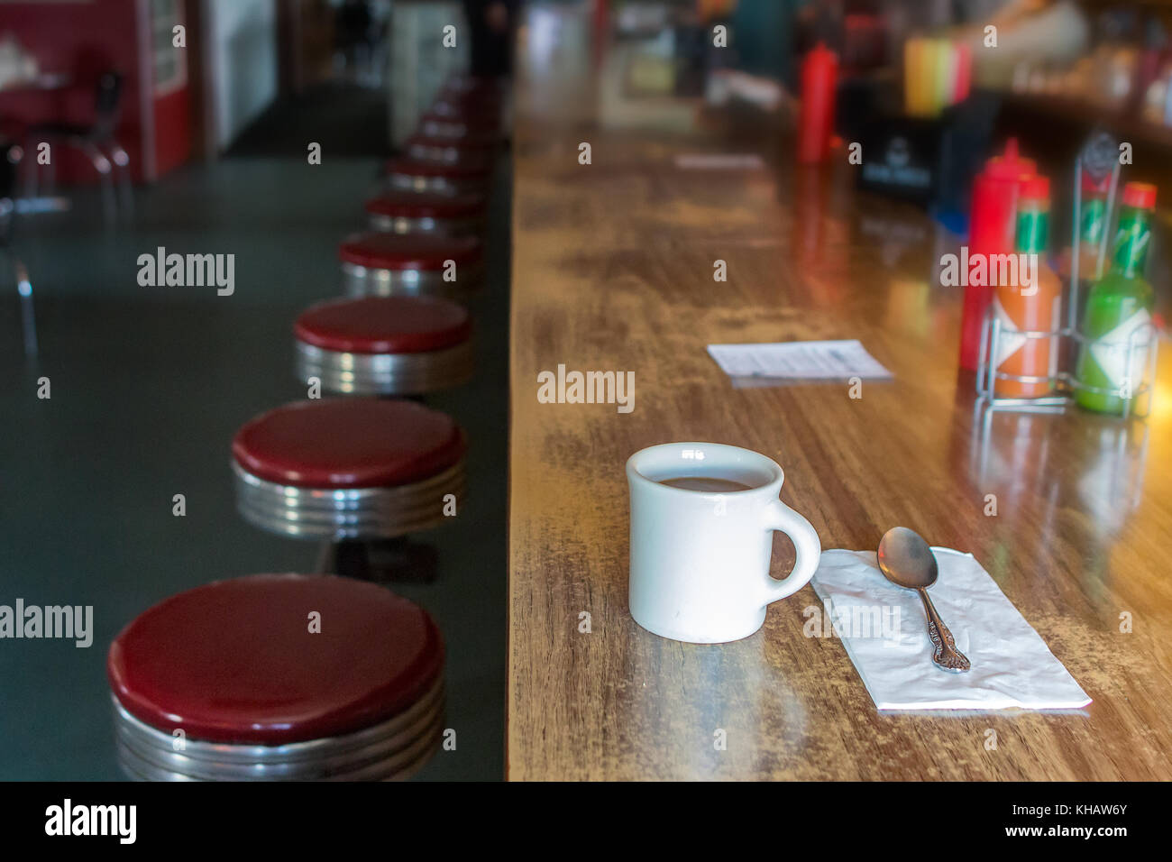 A white coffee mug and a spoon placed on the table of a traditional ...