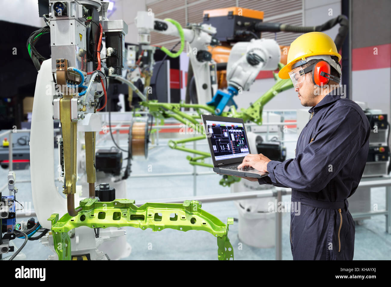 Engineer using laptop computer maintenance automatic robotic hand machine tool in automotive ...